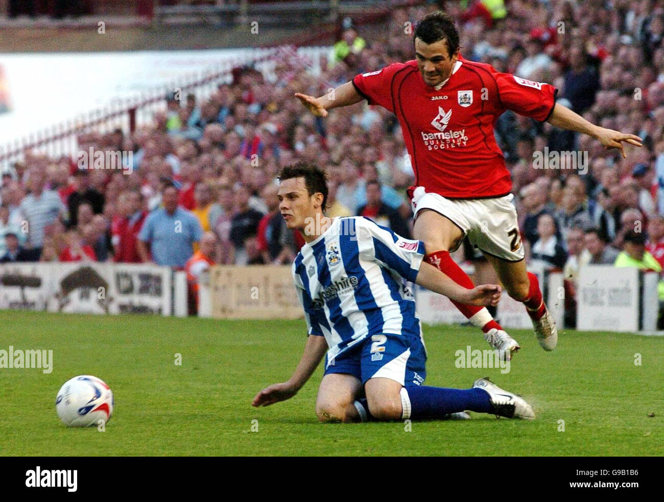 Barnsley's Martin Devaney jumps the challenge from Huddersfield Town's ...