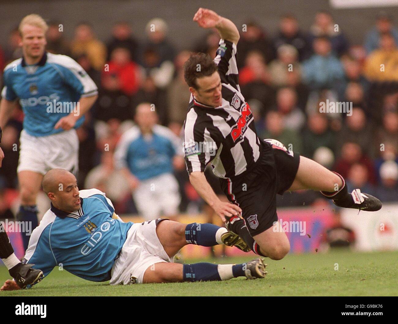 Manchester City's Richard Edghill (l) slides in on Grimsby Town's David ...