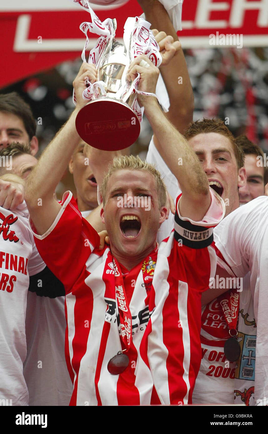 Cheltenham's captain John Finnigan lifts the trophy after the Coca-Cola ...
