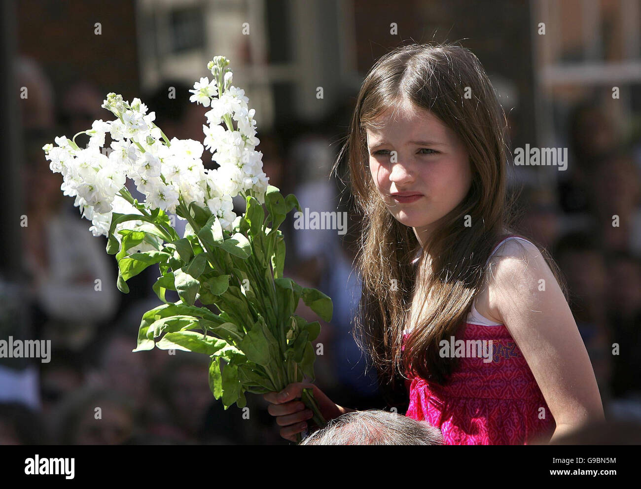 A young girl holds a bunch of white flowers as a symbol of protest at a ...