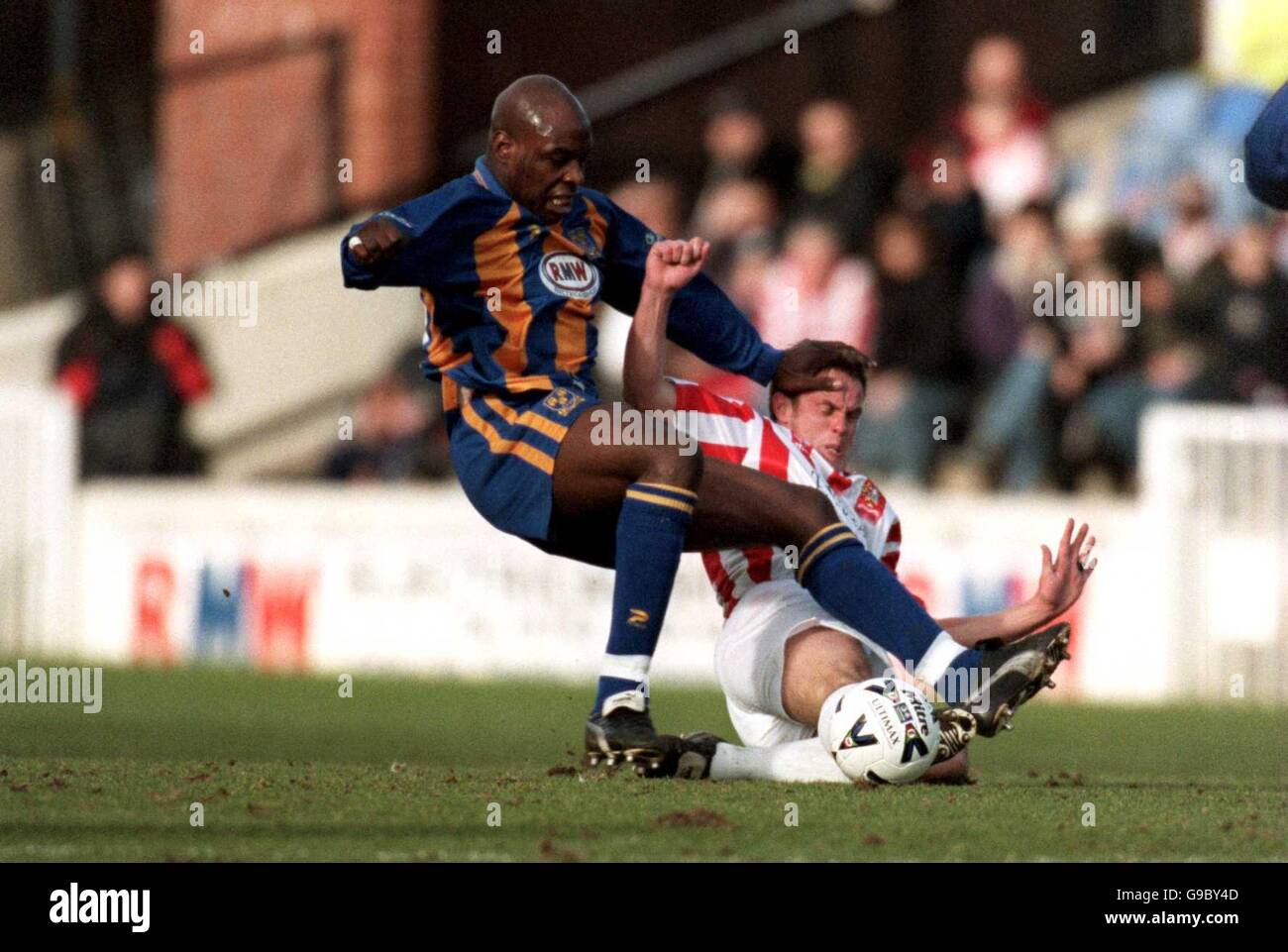 John Gayle of Shrewsbury Town (l) is slide tackled by Cheltenham Town's ...