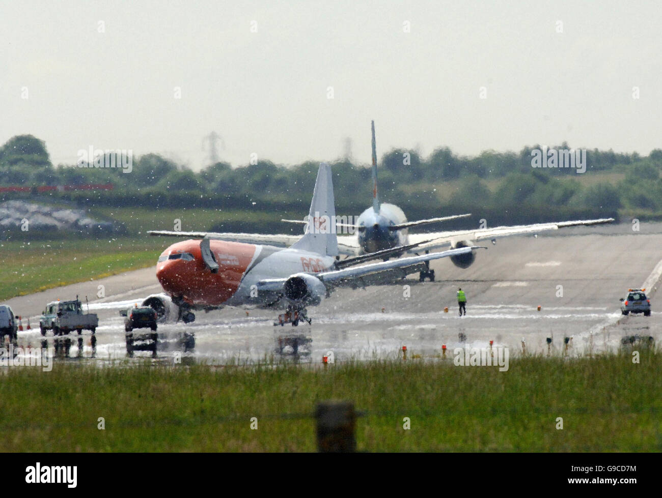 A TNT cargo plane lies damaged as a departing jet kicks up foam on the ...