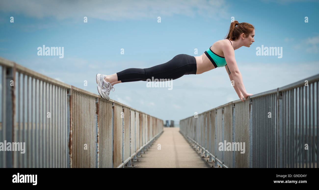 woman exercising outside, doing push ups between metal railings Stock ...