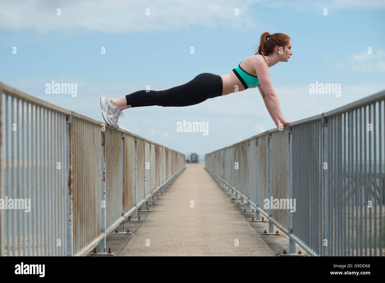 woman exercising outside, doing push ups between metal railings Stock ...