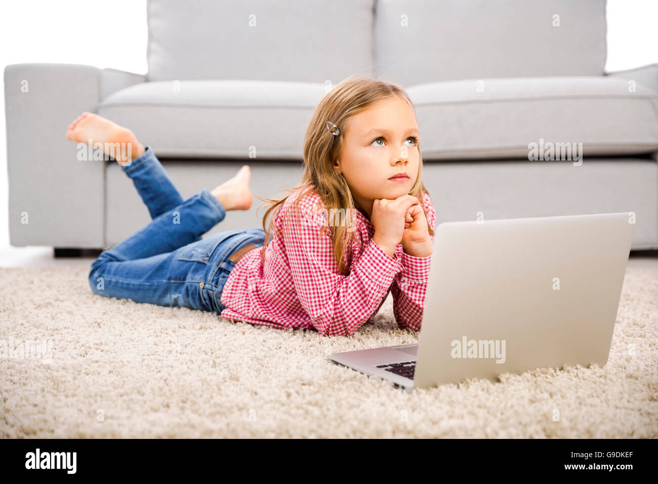 Happy little girl at home working with a laptop Stock Photo - Alamy