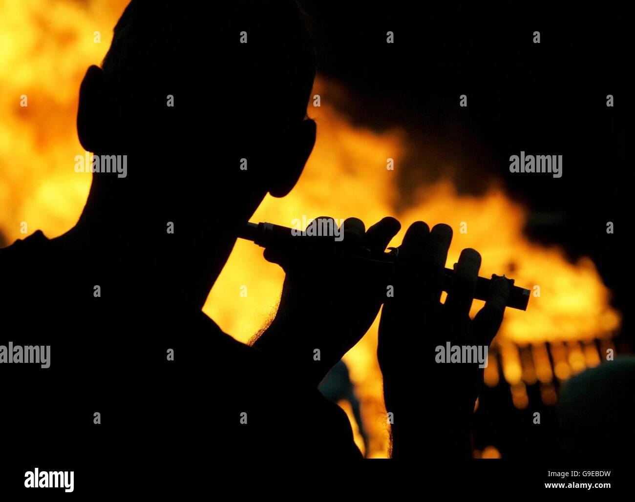 A man plays a flute in front of a bonfire on the Shankill road in ...