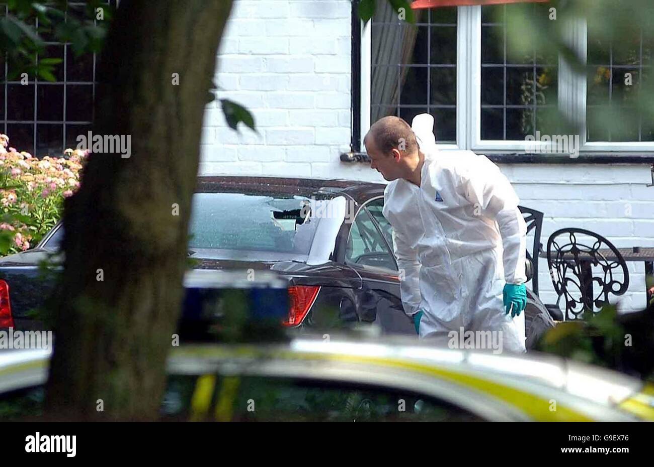 A police forensic officer studies damage to the rear window of a car ...