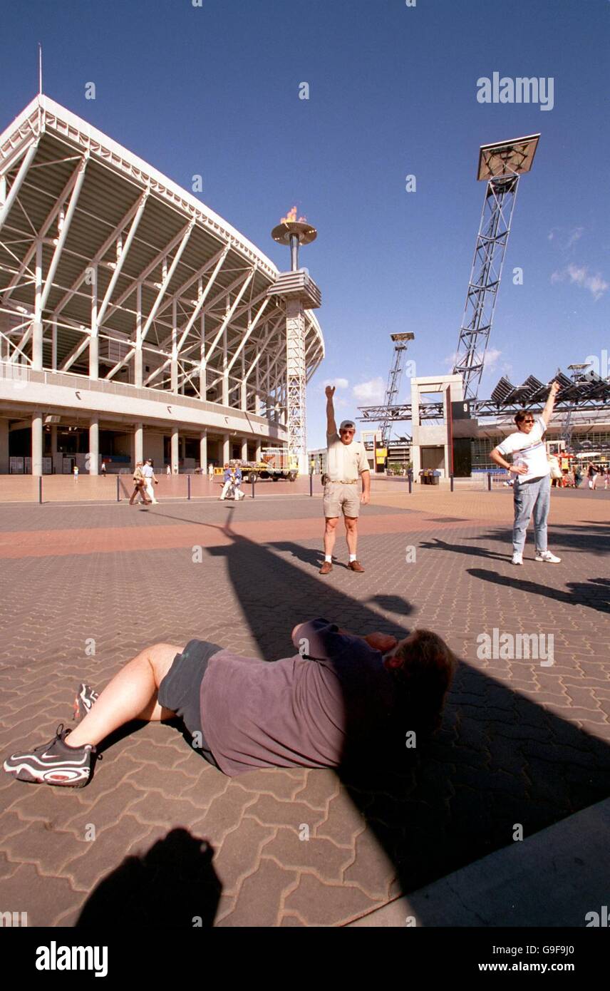 Fans pose for photographs as if they are holding the giant Olympic ...