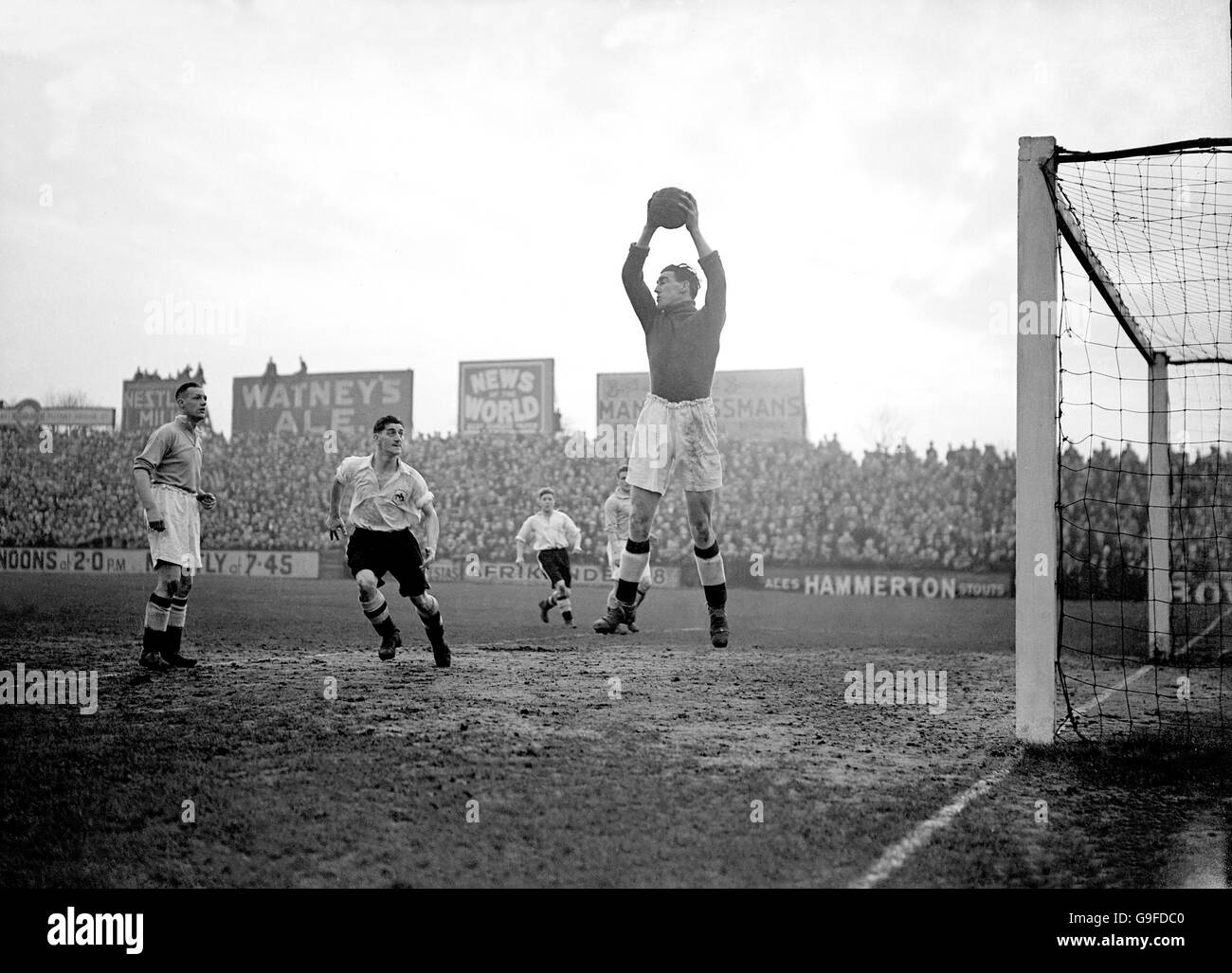 Manchester City goalkeeper Frank Swift (r) catches a cross, watched by ...