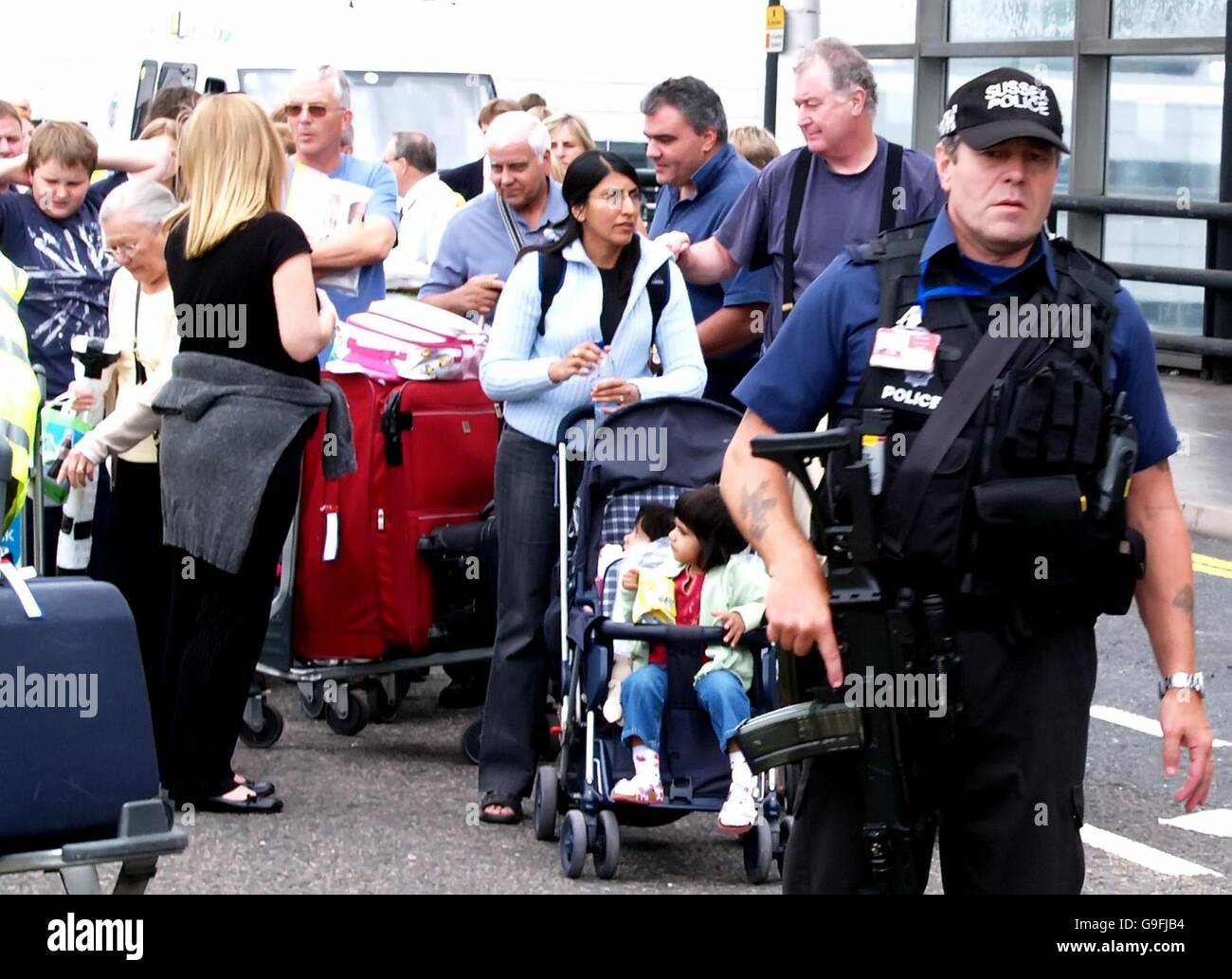 An armed policeman patrolling through passengers outside the departure ...