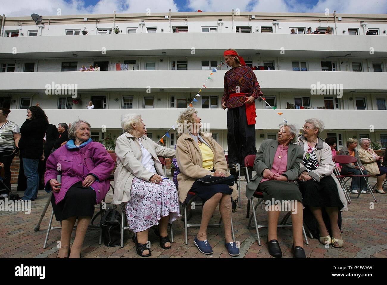 Pearse House residents watch a stilt-walker Stock Photo - Alamy