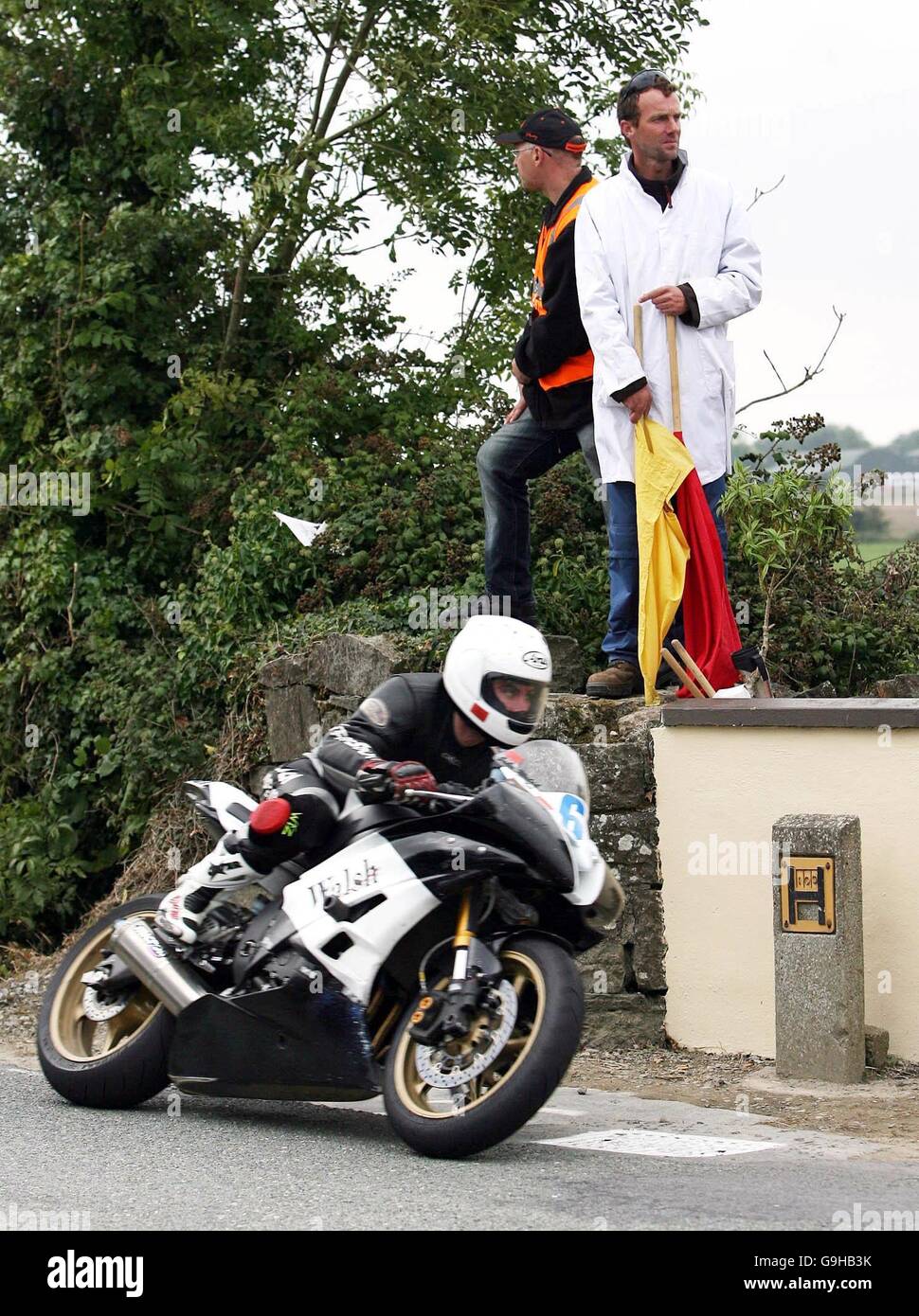 A competitor in the 250cc race passes stewards near to the spot where ...