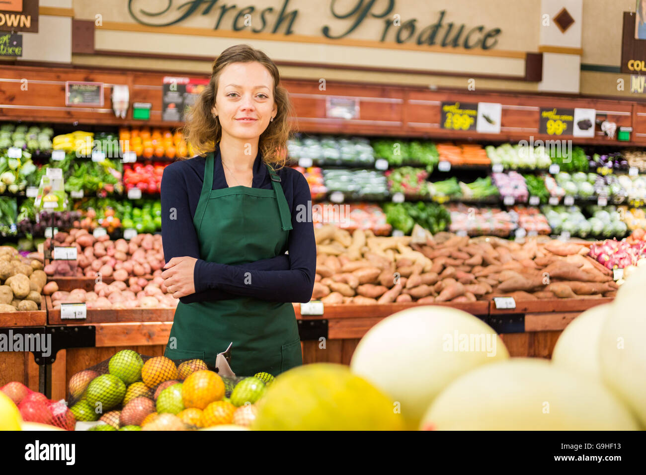 Portrait of a grociery store clerk in front of a vegetable section of ...
