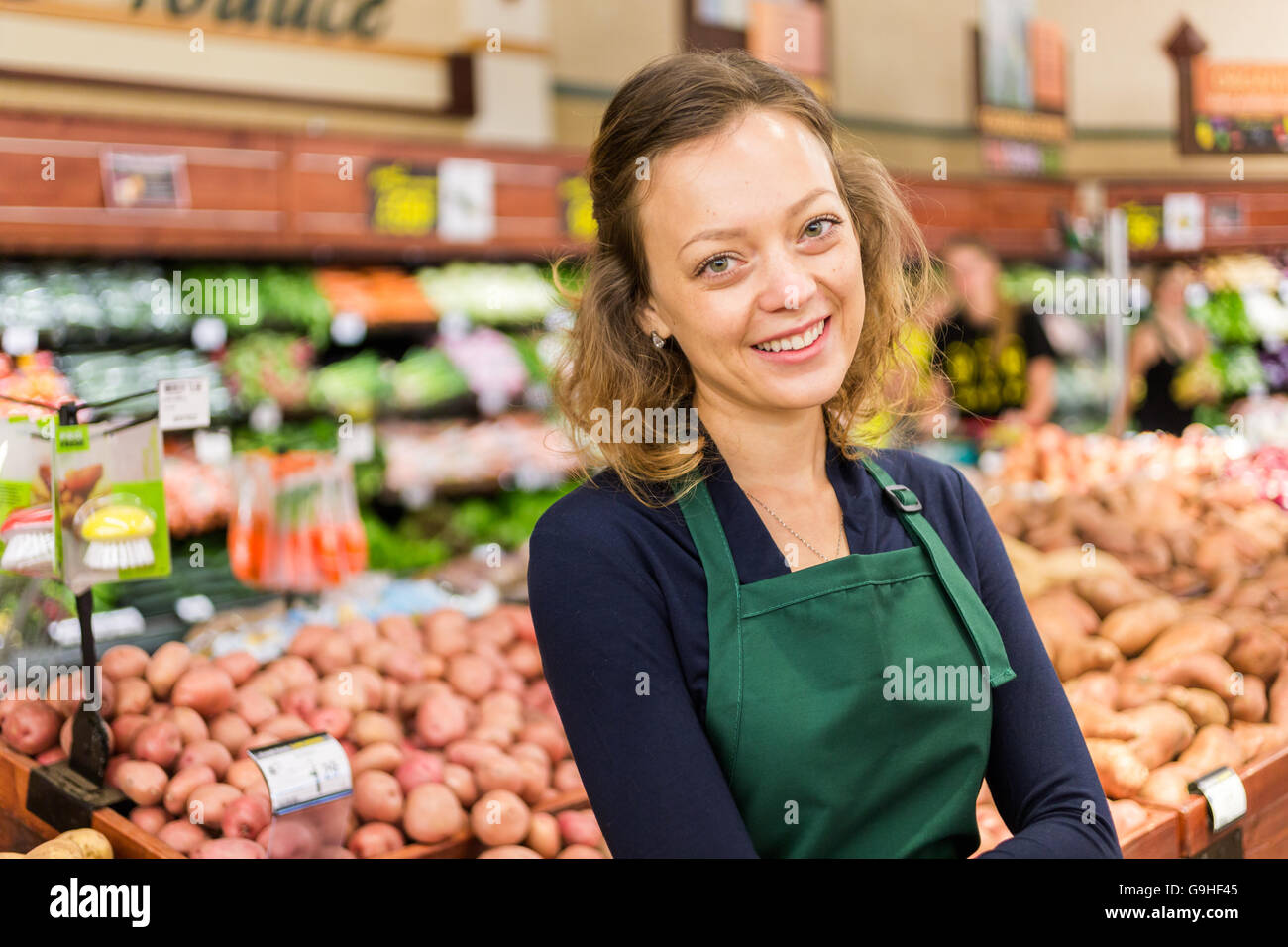 Portrait of a grociery store clerk in front of a vegetable section of ...