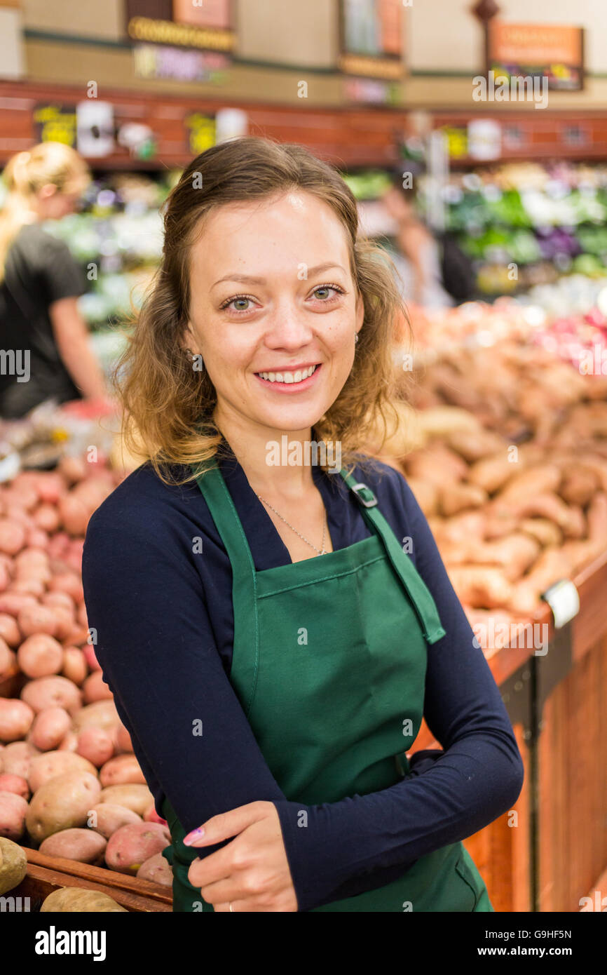 Portrait of a grociery store clerk in front of a vegetable section of ...