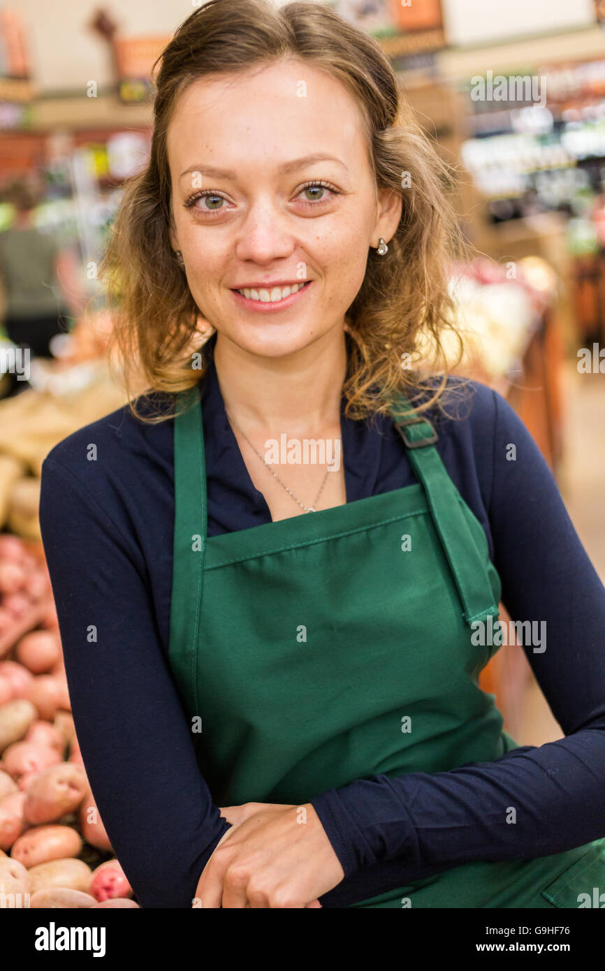 Portrait of a grociery store clerk in front of a vegetable section of ...