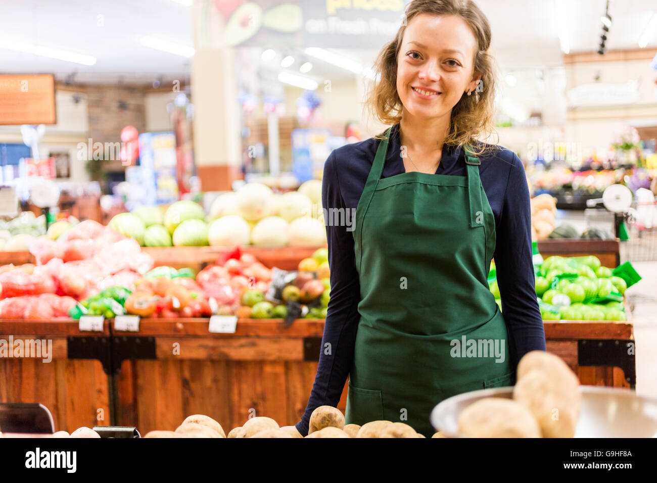 Portrait of a grociery store clerk in front of a vegetable section of ...