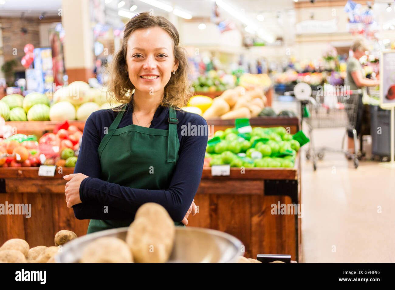 Portrait of a grociery store clerk in front of a vegetable section of ...