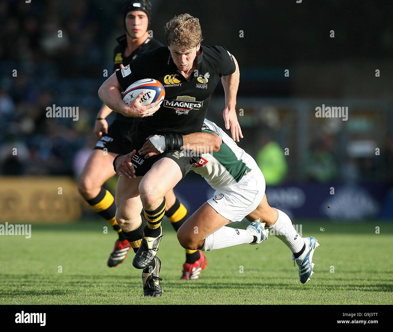 Wasps Tom Rees breaks through the tackle of London Irish Riki Flutey ...