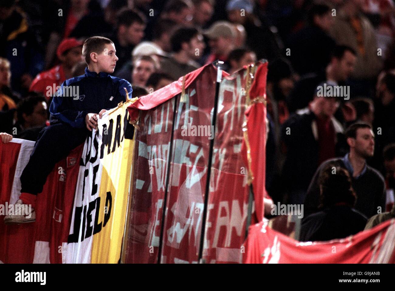 A young Liverpool fan sits on a wall and watches his side in action ...