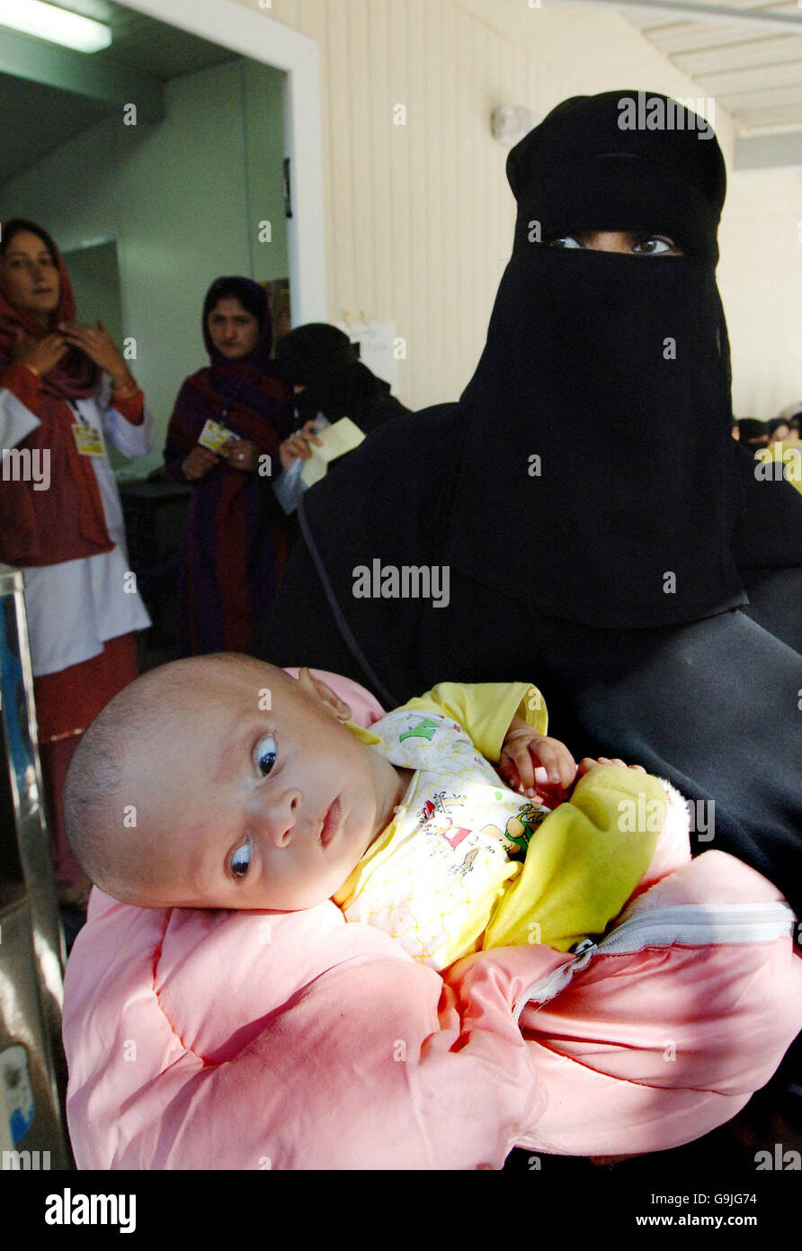 A woman brings her child to the Red Cross and Red Crescent Clinic as ...