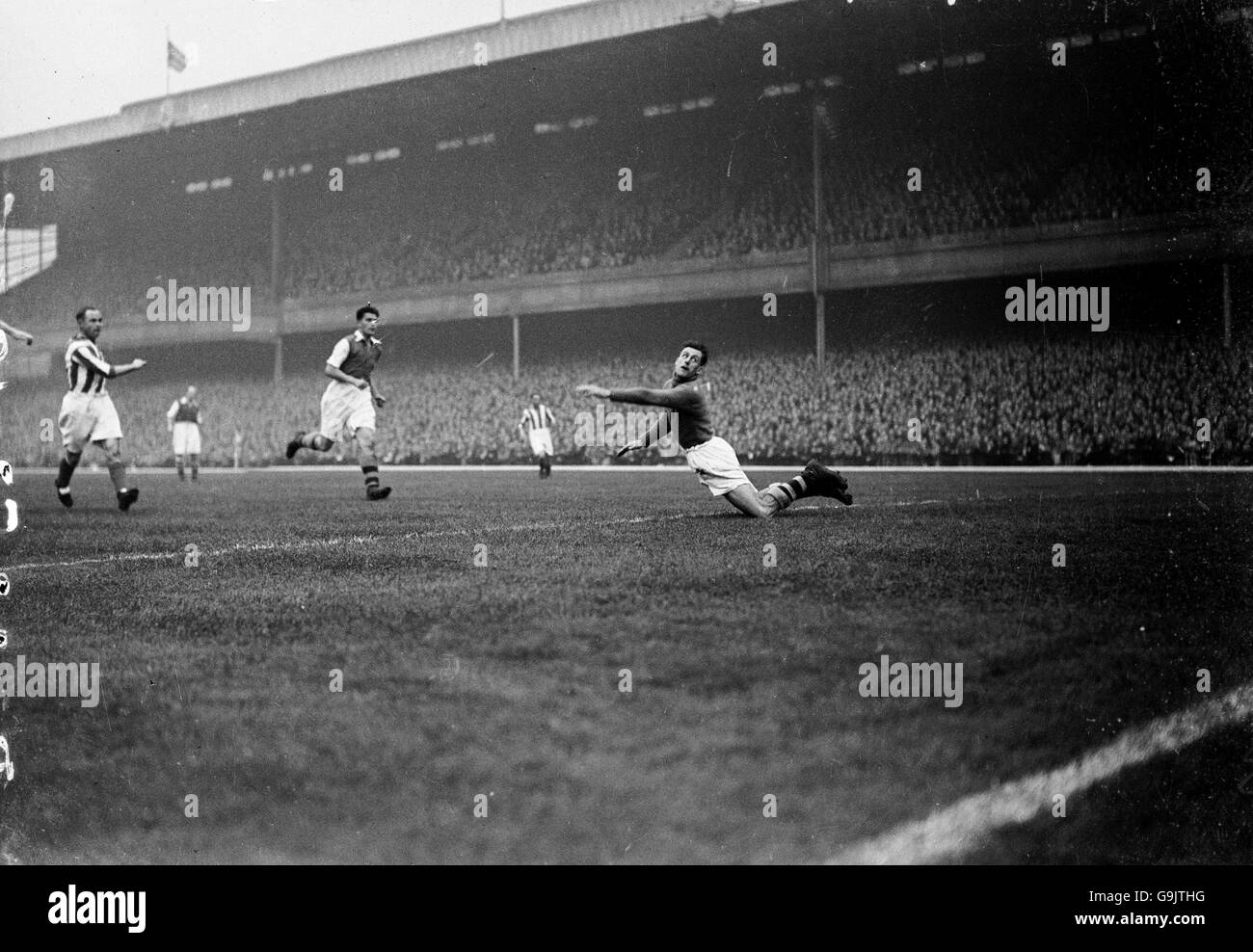 Arsenal's Les Compton (c) looks on as goalkeeper George Swindin (r) is ...