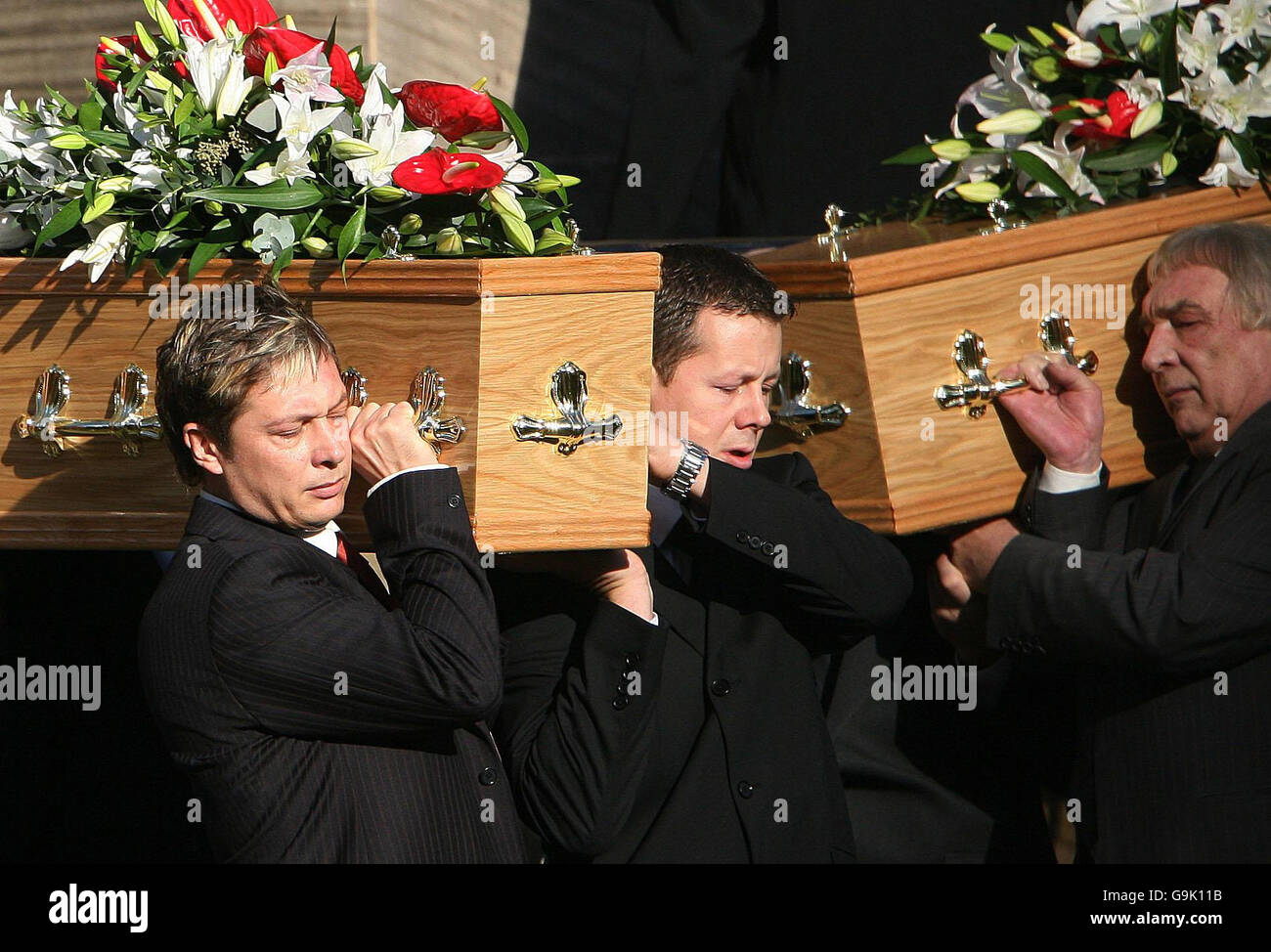 Neil Shepherd (left), the children's father, carries one of the coffins ...