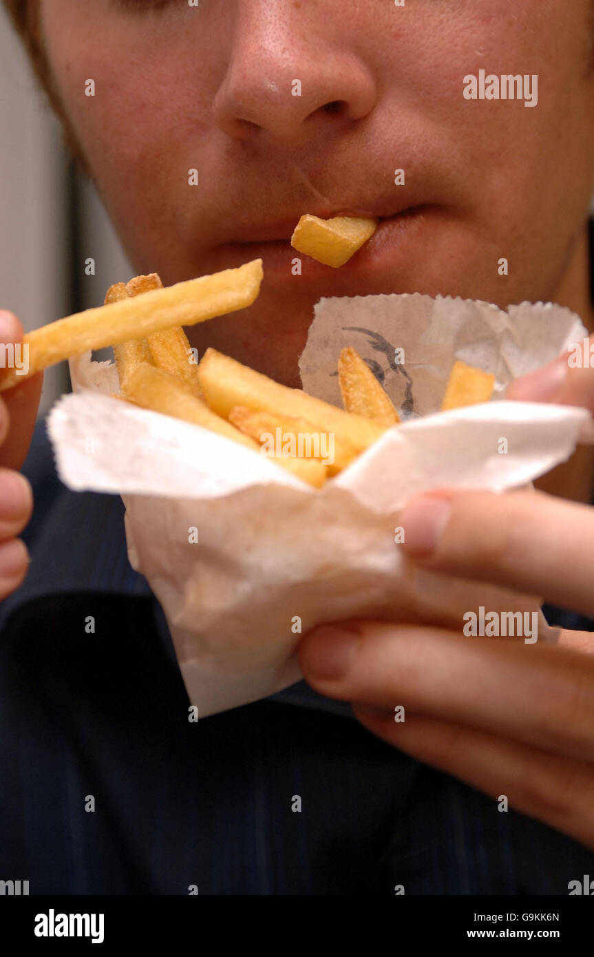 KFC pedges to stop using unhealthy trans fats. A man eats chips from ...