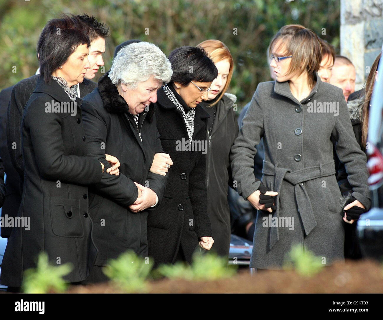 Family members (names or relationship not known) walk behind the coffin ...