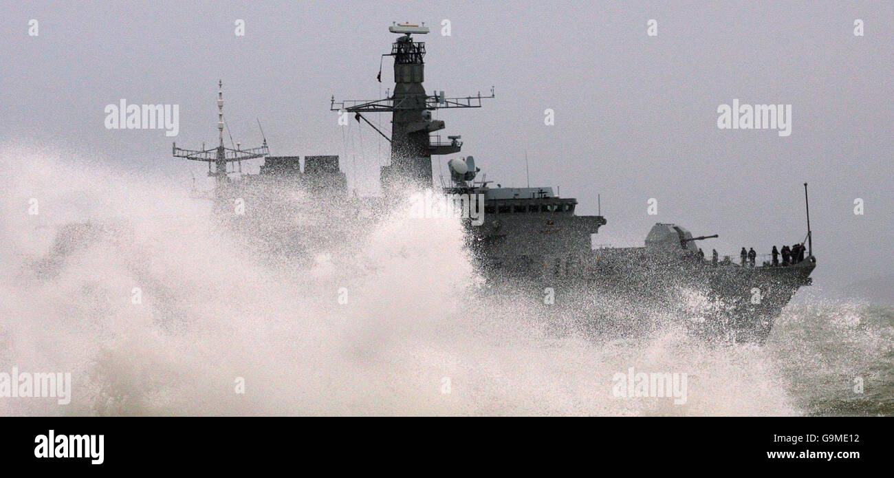 Photo. A naval vessel arrives into Portsmouth harbour as waves crash ...