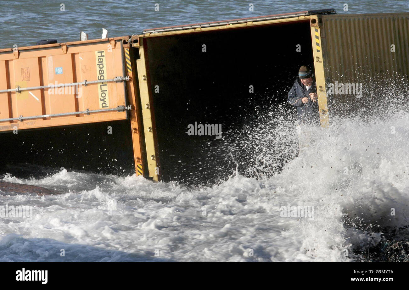 A beachcomber inspects the contents of a washed-up container near ...