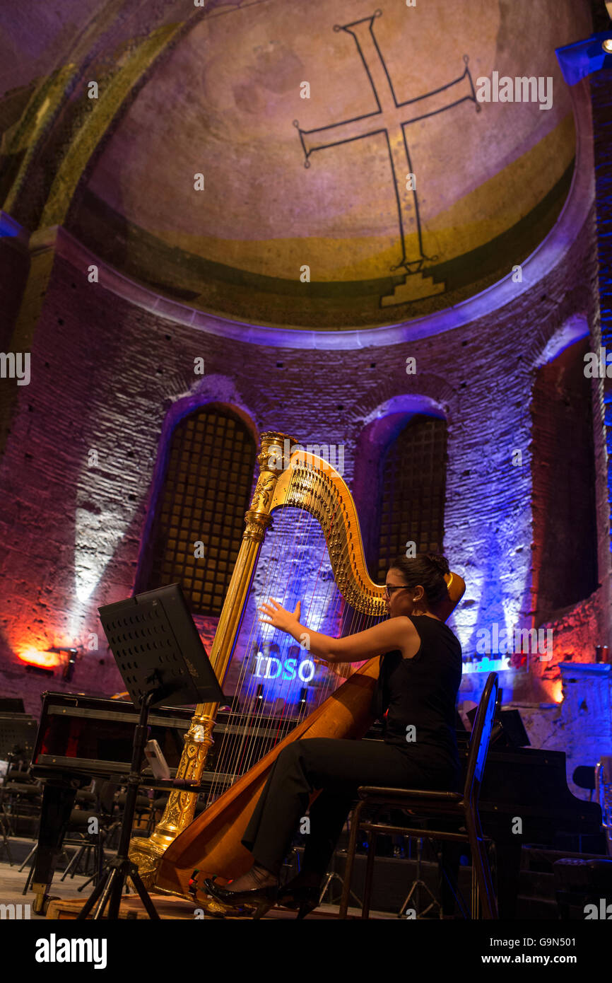 A woman who is playing harp on a ceremony in Hagia Irene church.It is ...