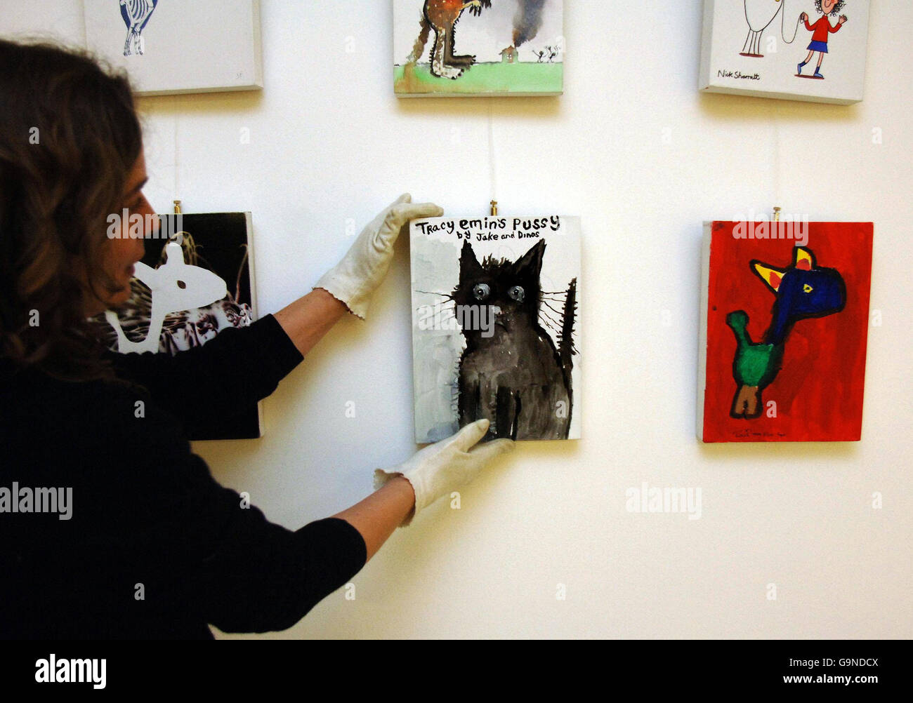 Artist Emma Harding adjusts a picture by artists Jake and Dinos Chapman ...