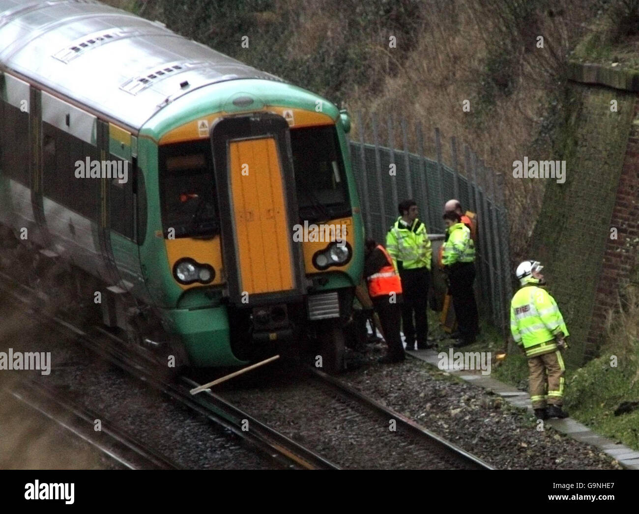 Railway workers and emergency service personnel stand next to the front ...