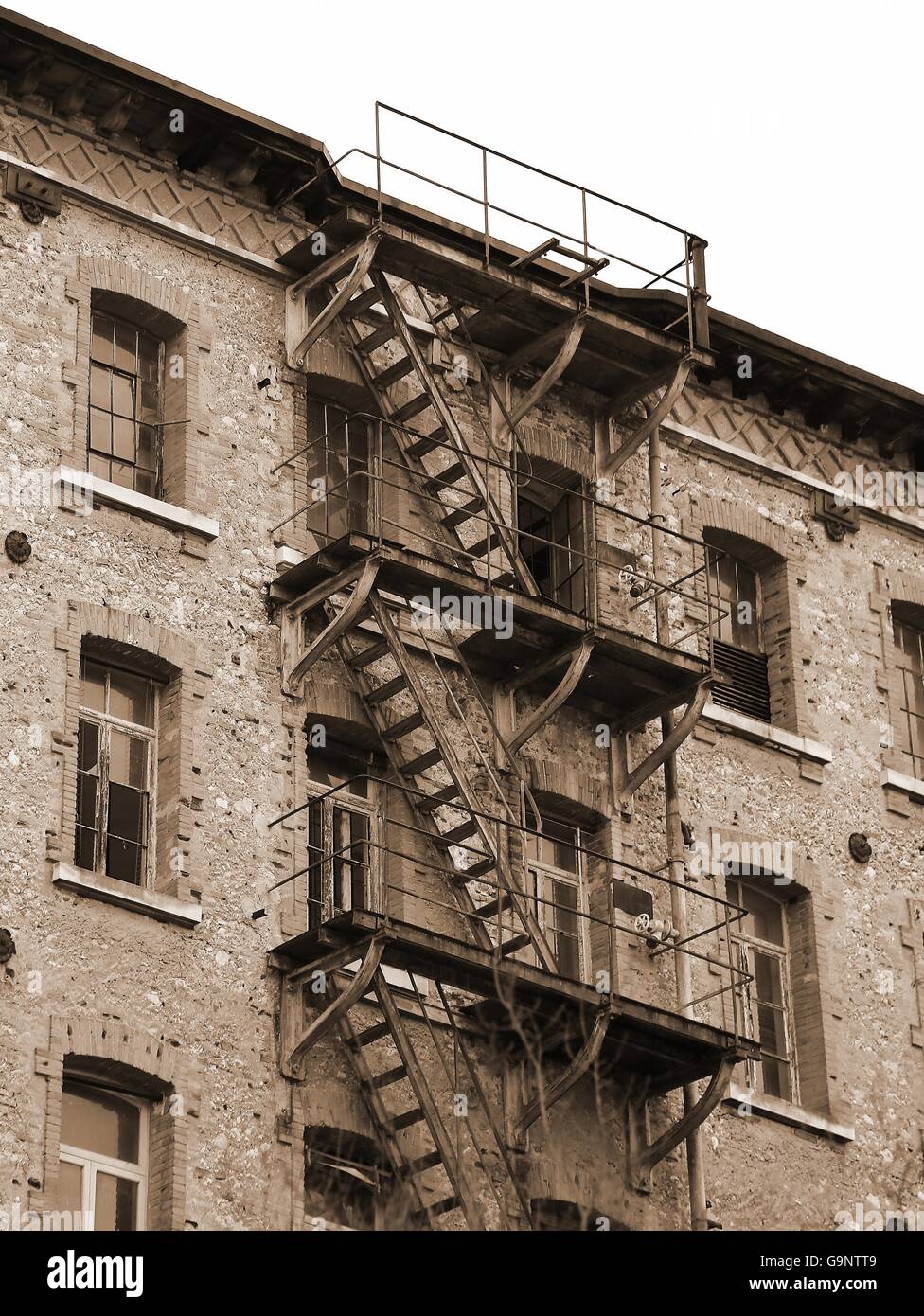 dilapidated industrial building with rusty fire escape with facing ...