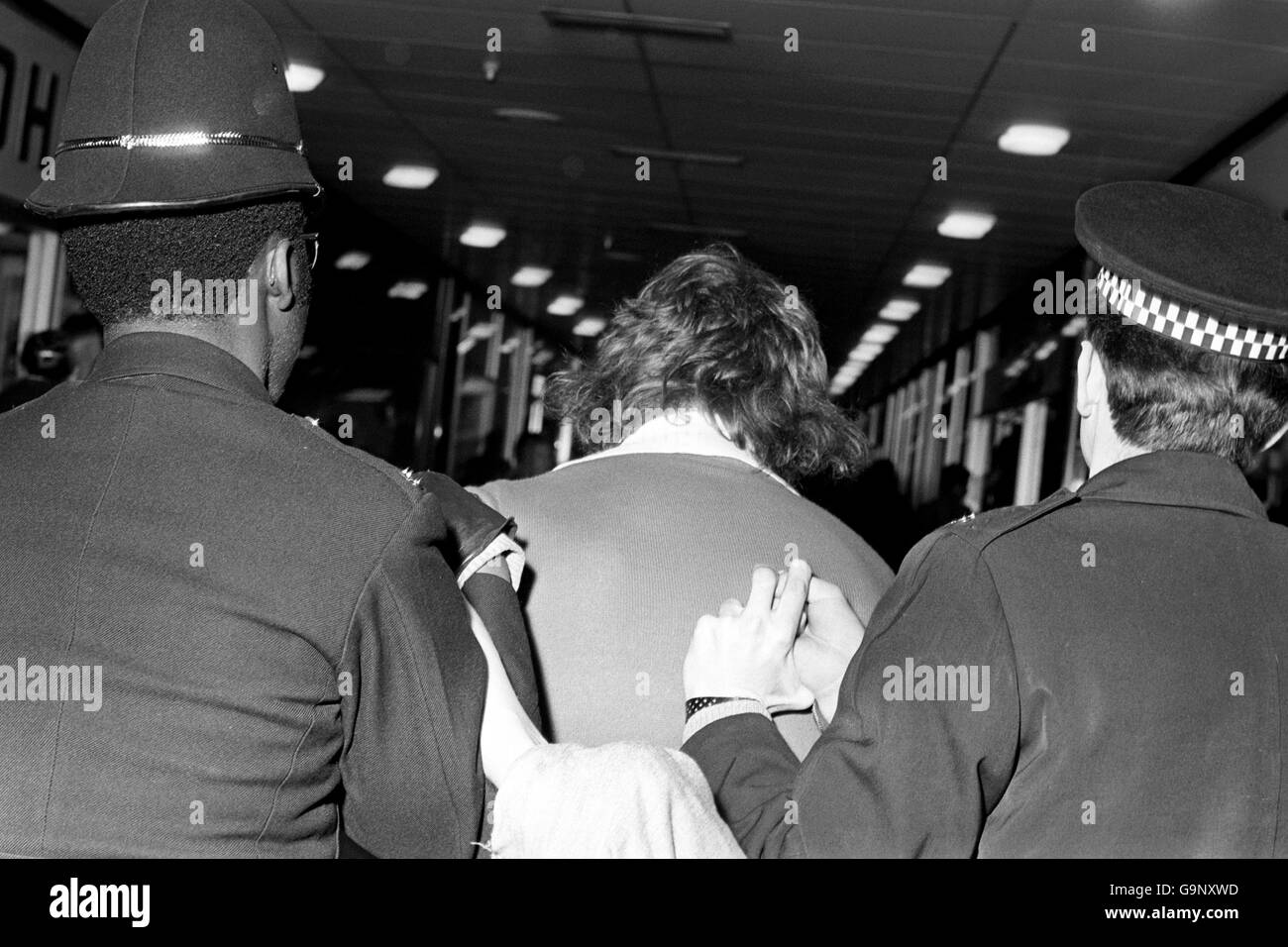 A fan is led away by two police officers after being arrested at ...