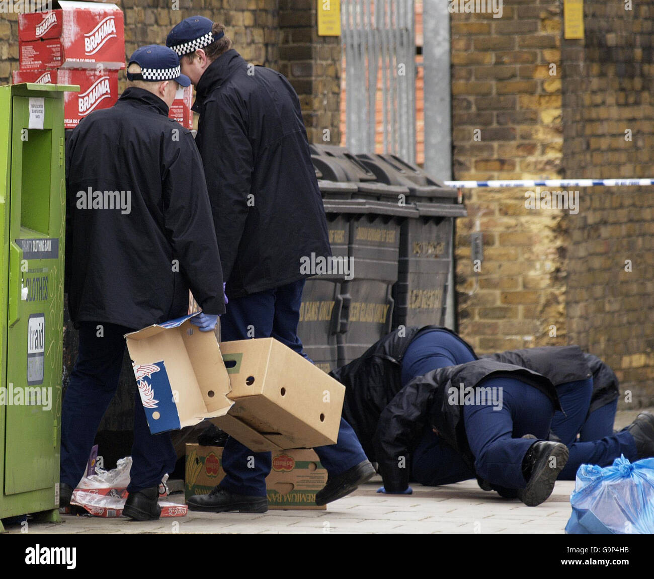 Police officers go through bins as they search the scene of a shooting ...