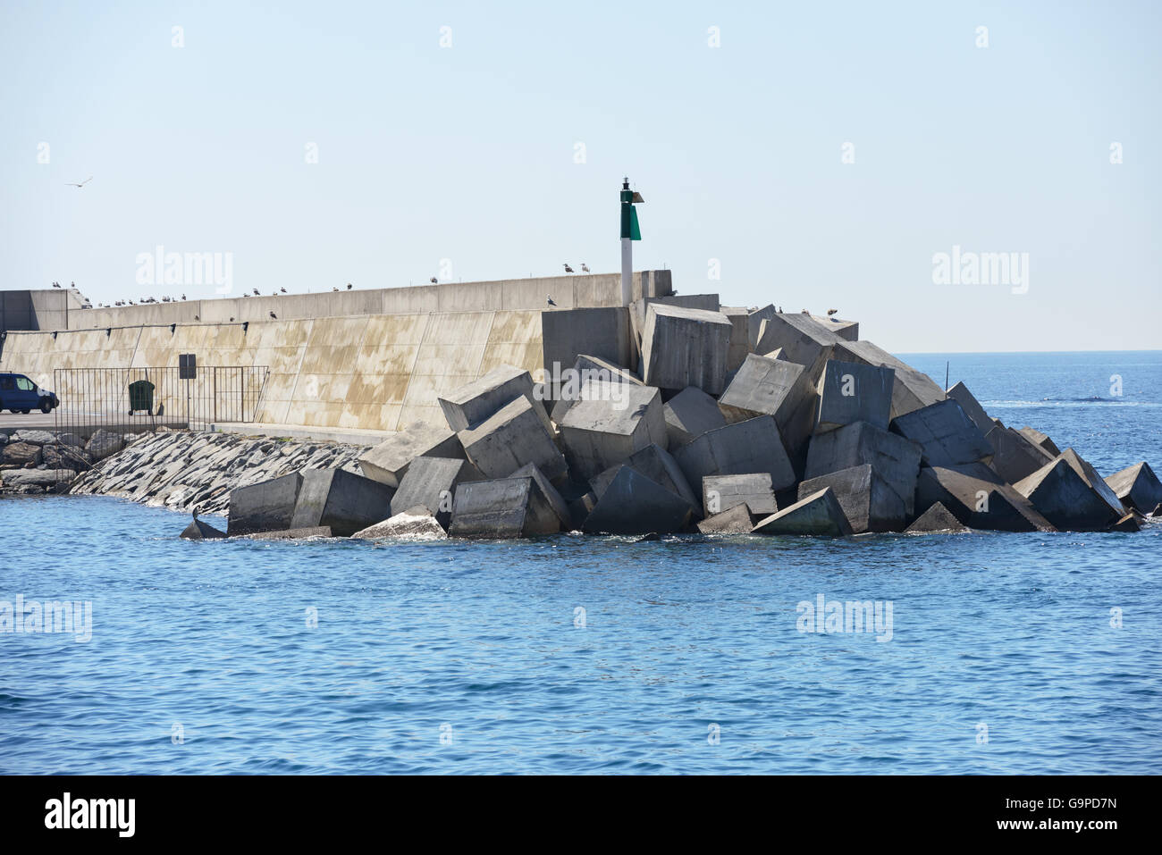 Concrete wall of breakwater with shaped cubic armour units at entrance ...