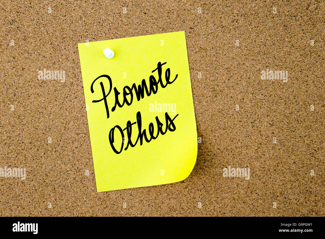 Promote Others written on yellow paper note pinned on cork board with ...