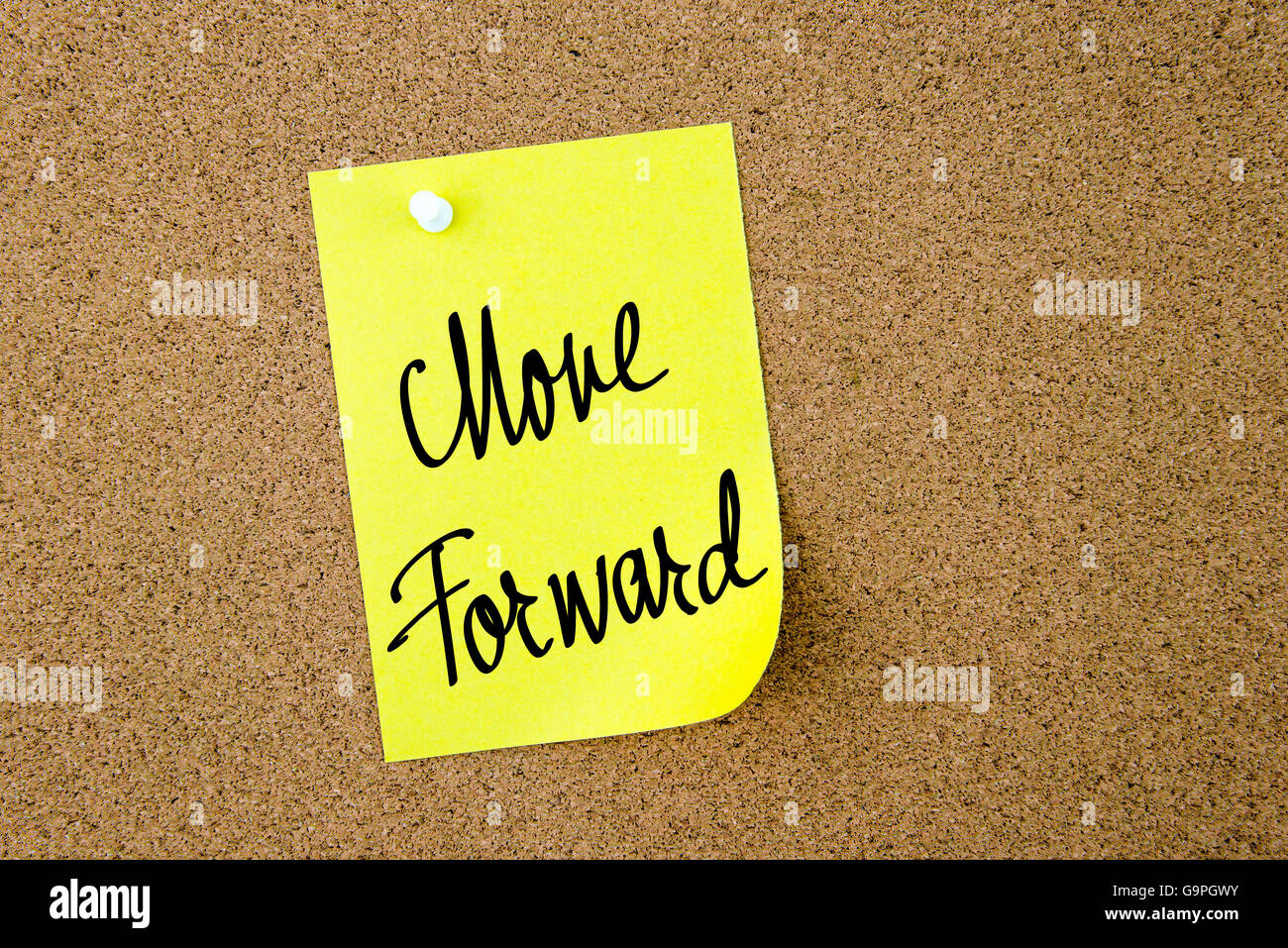 Move Forward written on yellow paper note pinned on cork board with ...