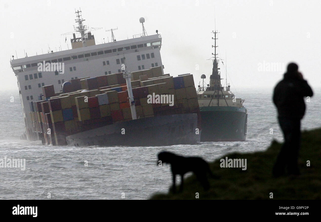 A man walks his dog as the grounded cargo ship MSC Napoli, sits a mile ...