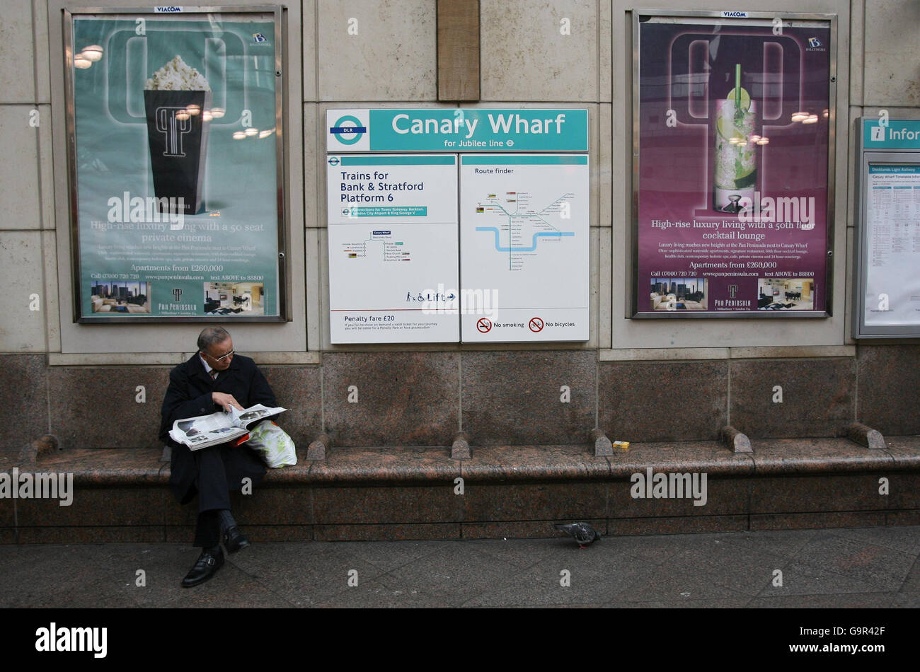 A commuter reads a newspaper as he waits for a train at Canary Wharf ...