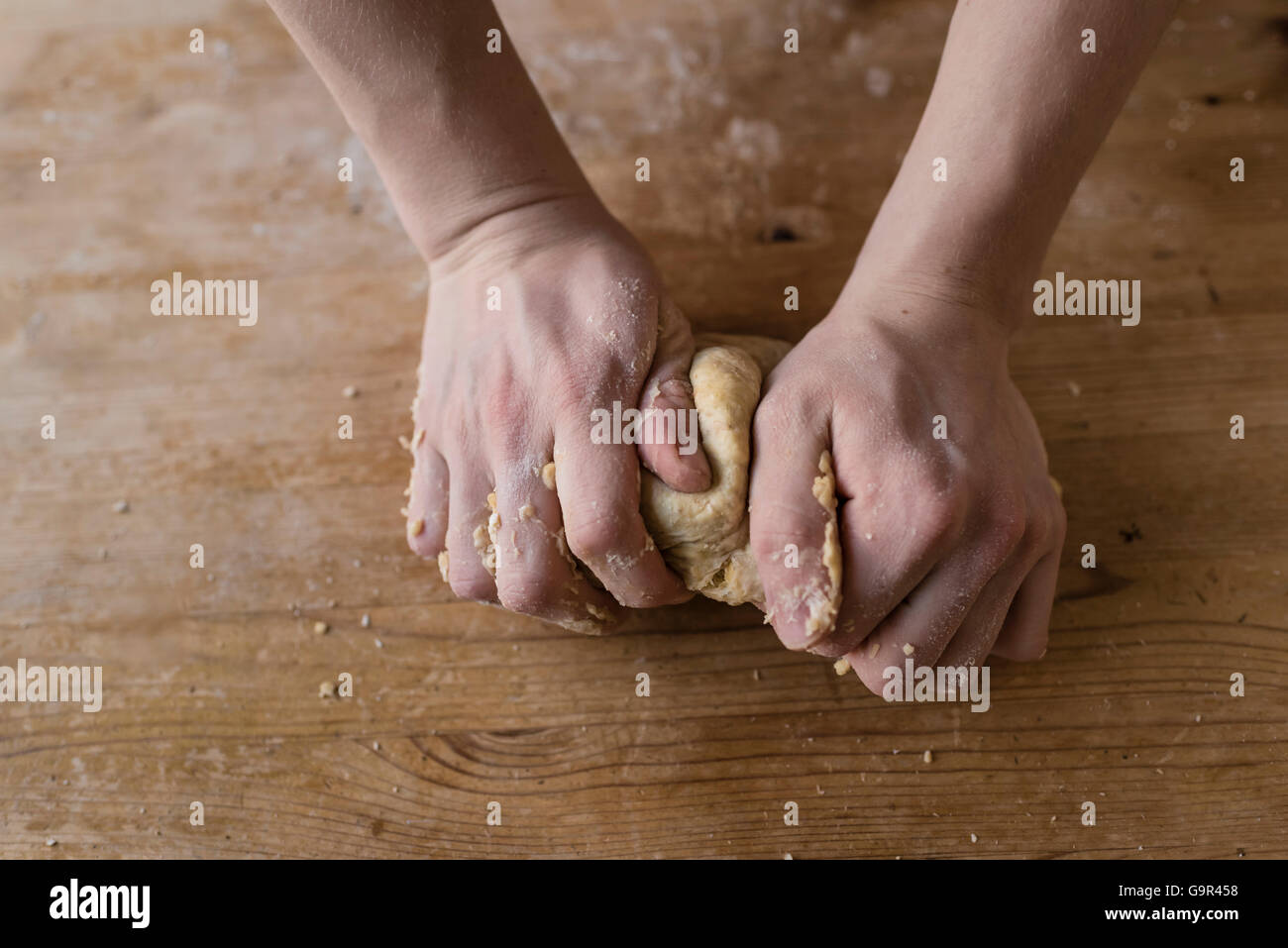 Close-up of two strong hands of a baker that are manually kneading ...