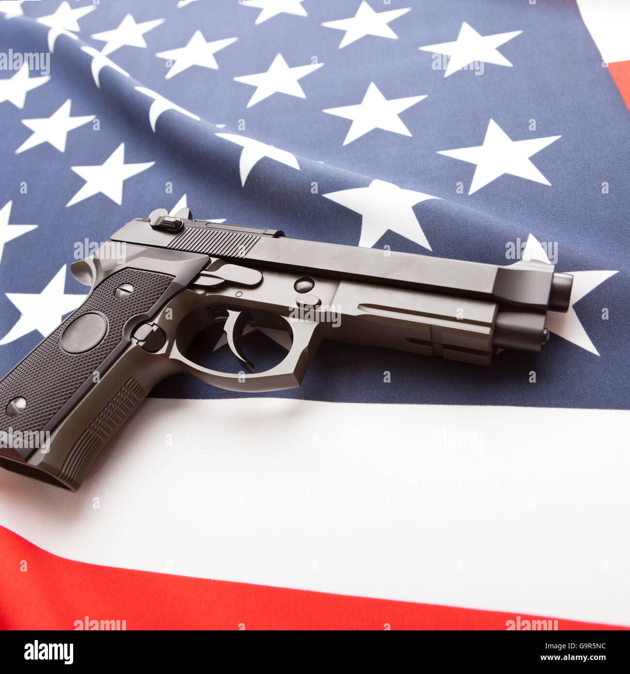 Part of close up studio shot of national flag with hand gun over it ...