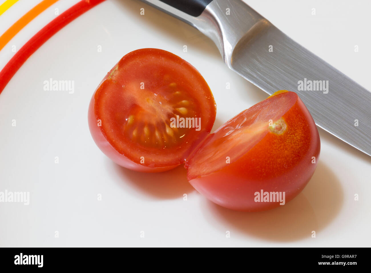 A single red tomato sliced open with a knife Stock Photo - Alamy