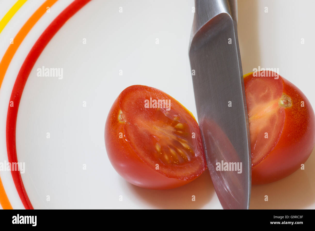 A single red tomato sliced open with a knife Stock Photo - Alamy