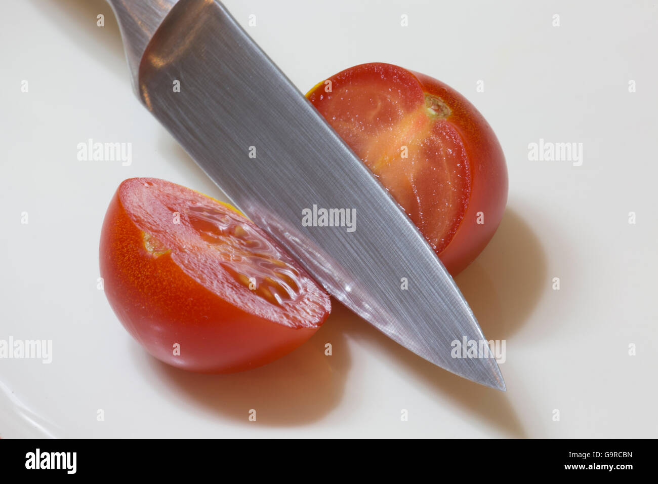 A single red tomato sliced open with a knife Stock Photo - Alamy
