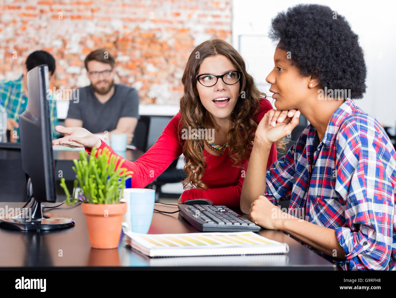 Two colleagues woman talking discussing sitting office desk Stock Photo ...