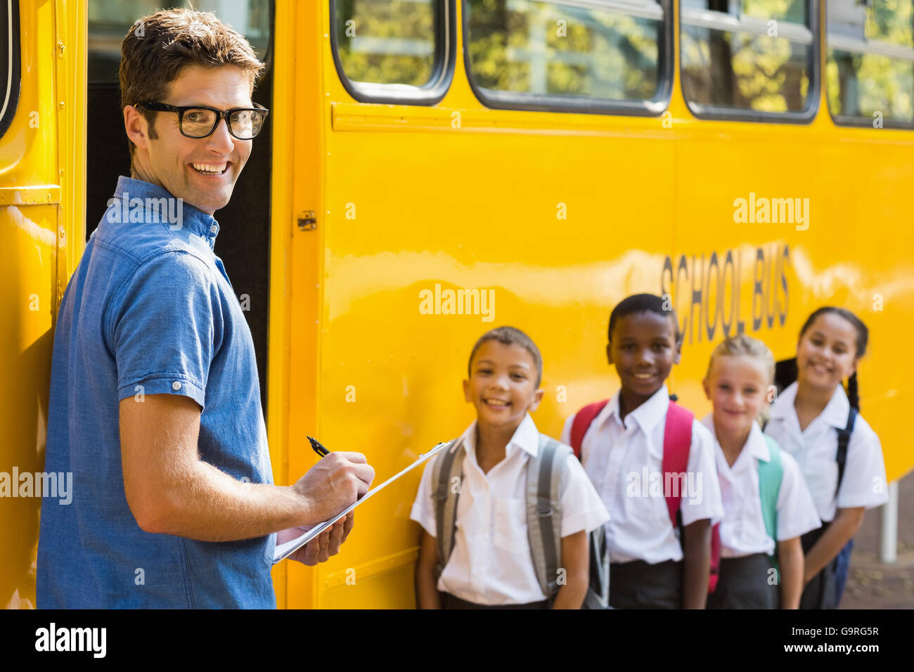 Smiling teacher updating check list of kids while entering in bus Stock ...