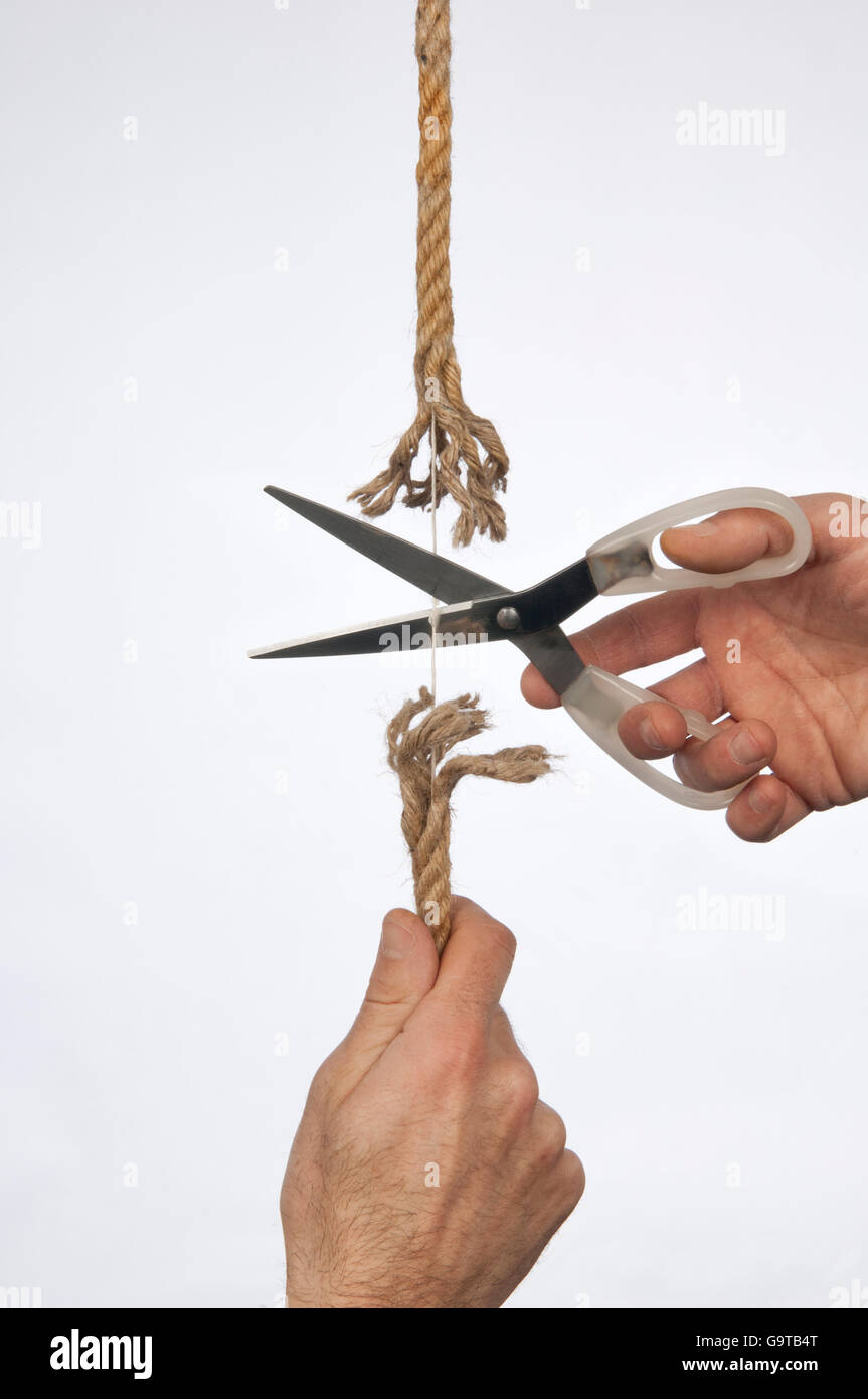 Hand holds a rope, scissors cuts the same string Stock Photo - Alamy
